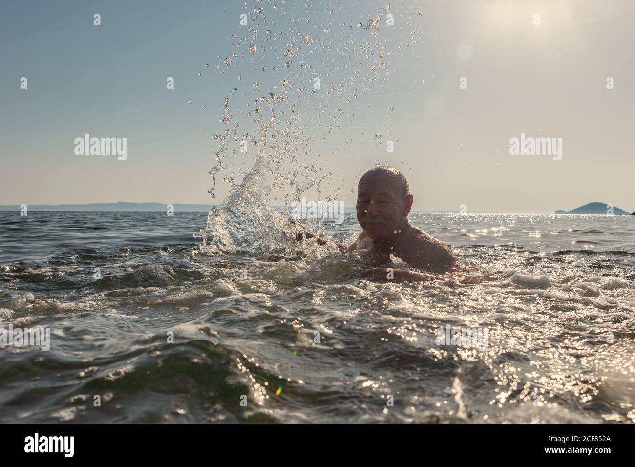 Bald mustache elderly man enjoying and splashing water looking at ...