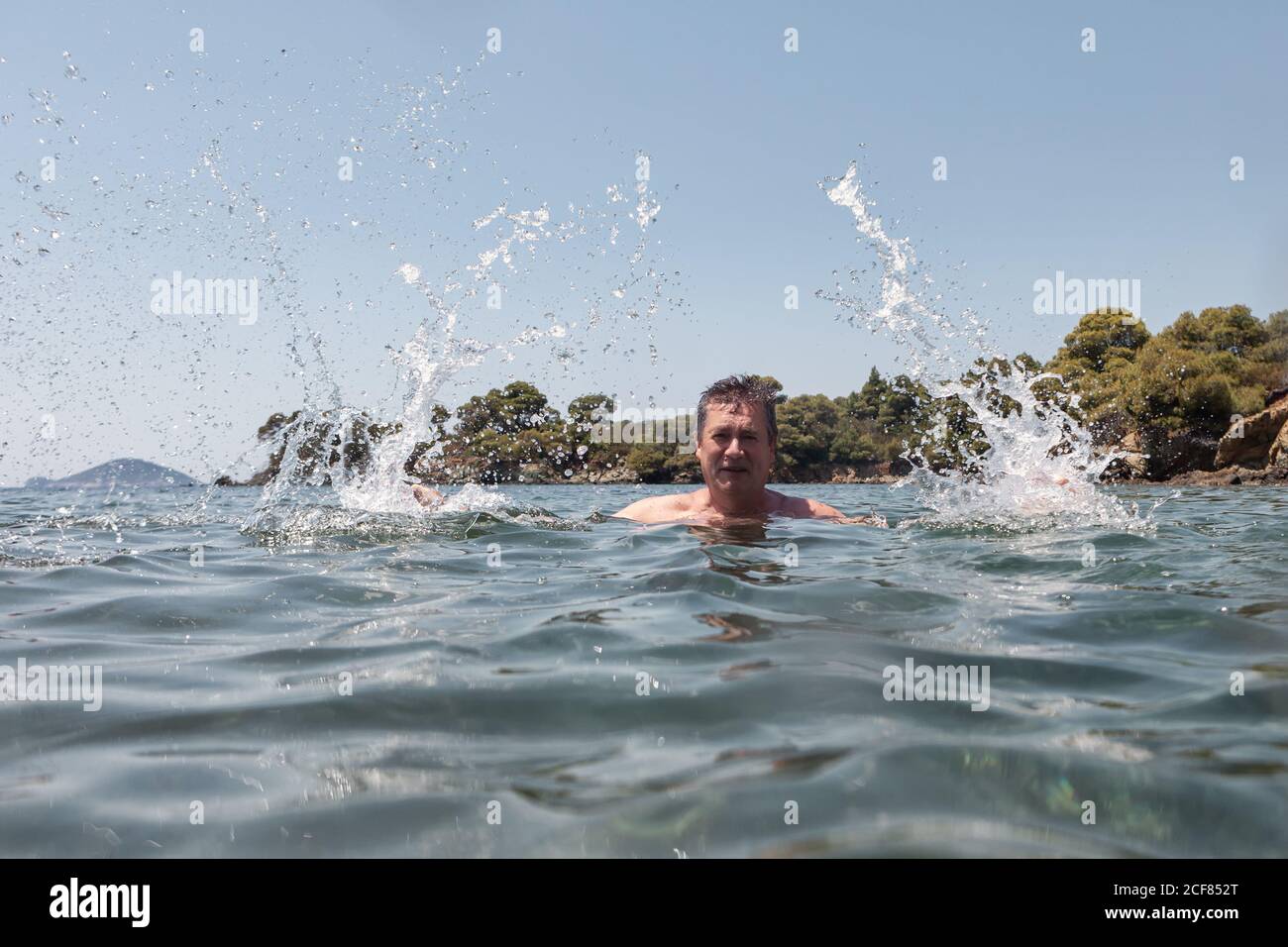 Bald mustache elderly man enjoying and splashing water looking at ...