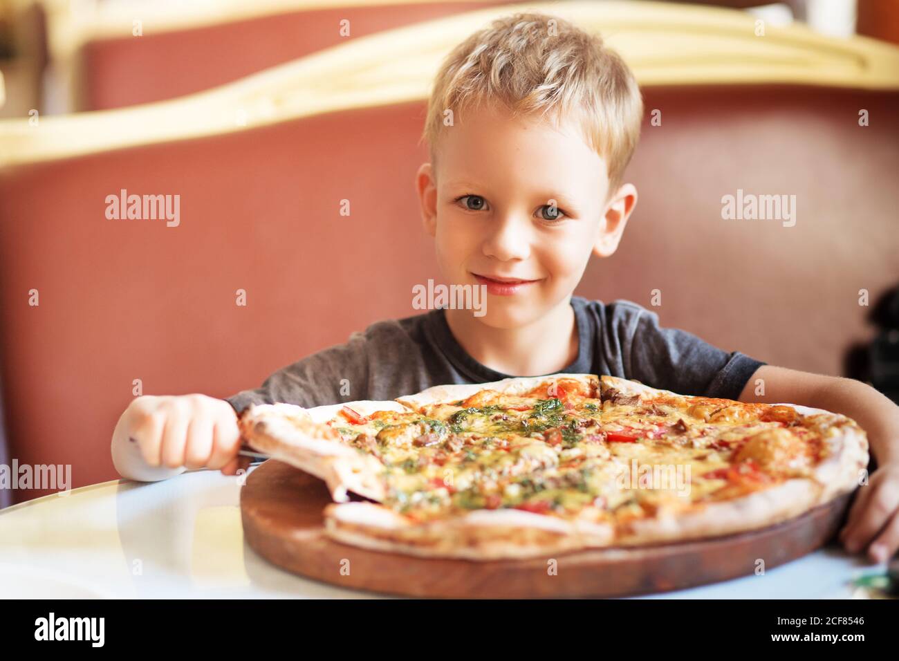 Children eat Italian pizza in the cafe. Adorable little boy eating ...