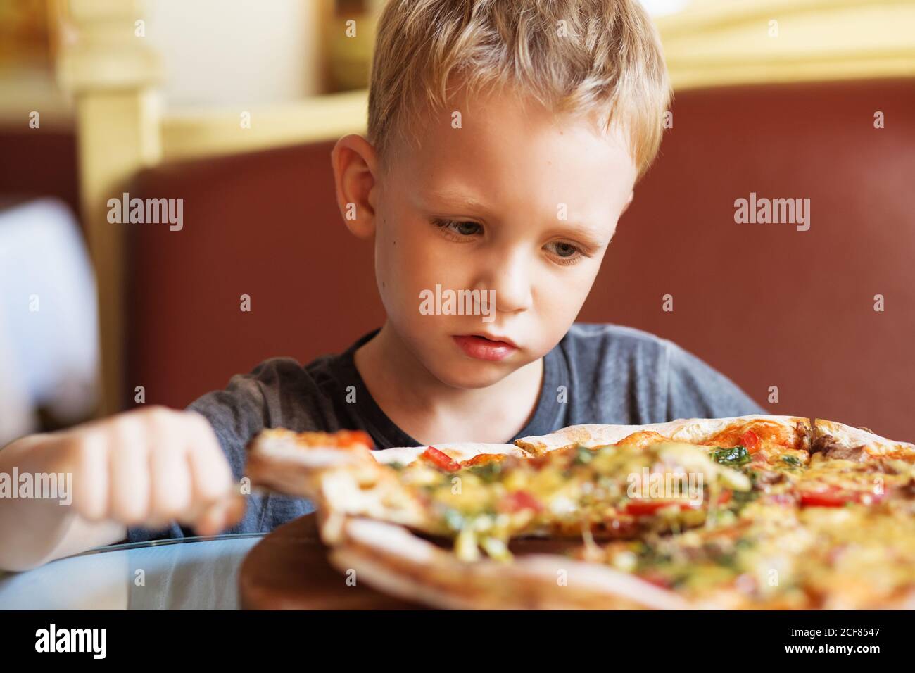 Children eat Italian pizza in the cafe. Adorable little boy eating ...
