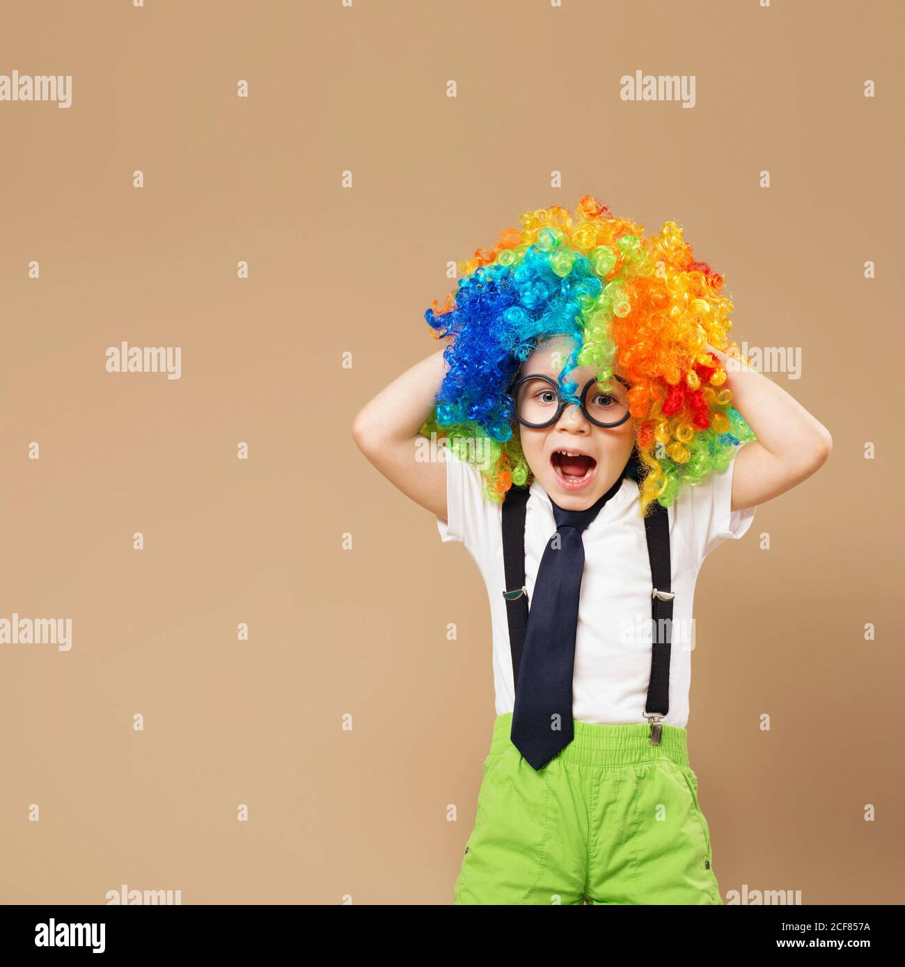 Blithesome children. Happy clown boy with large colorful wig. Close-up ...