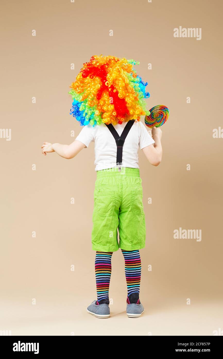 Happy clown boy in large colorful wig. Let's party! Funny kid clown. 1 ...