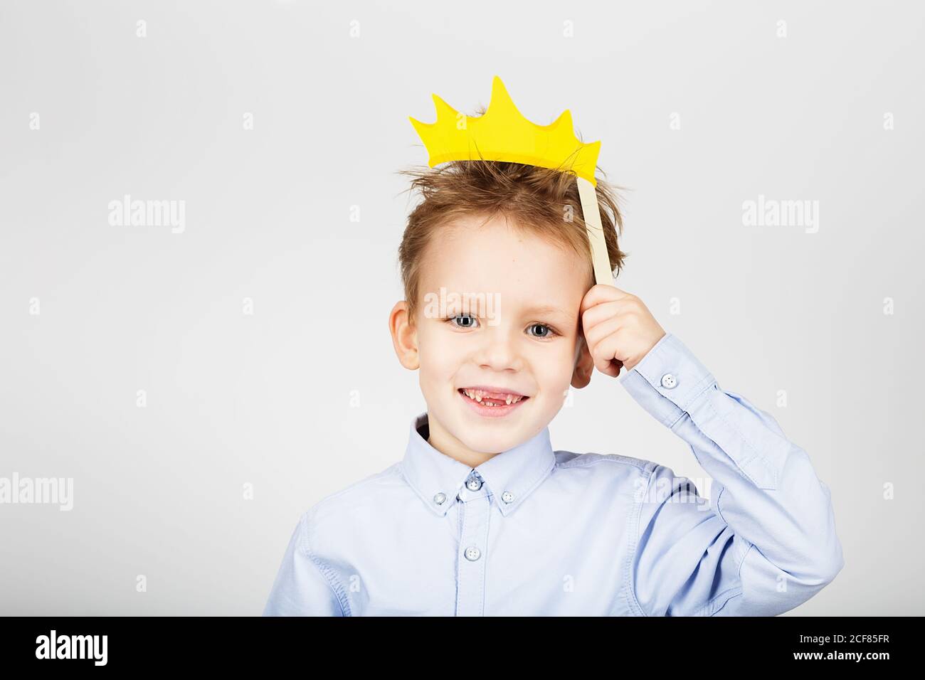 Portrait of a cute little school boy with yellow paper crown against a ...