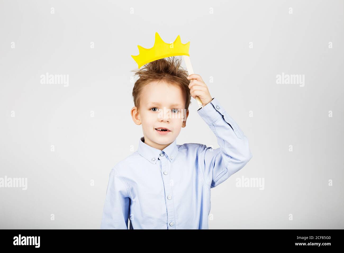 Portrait of a cute little school boy with yellow paper crown against a ...