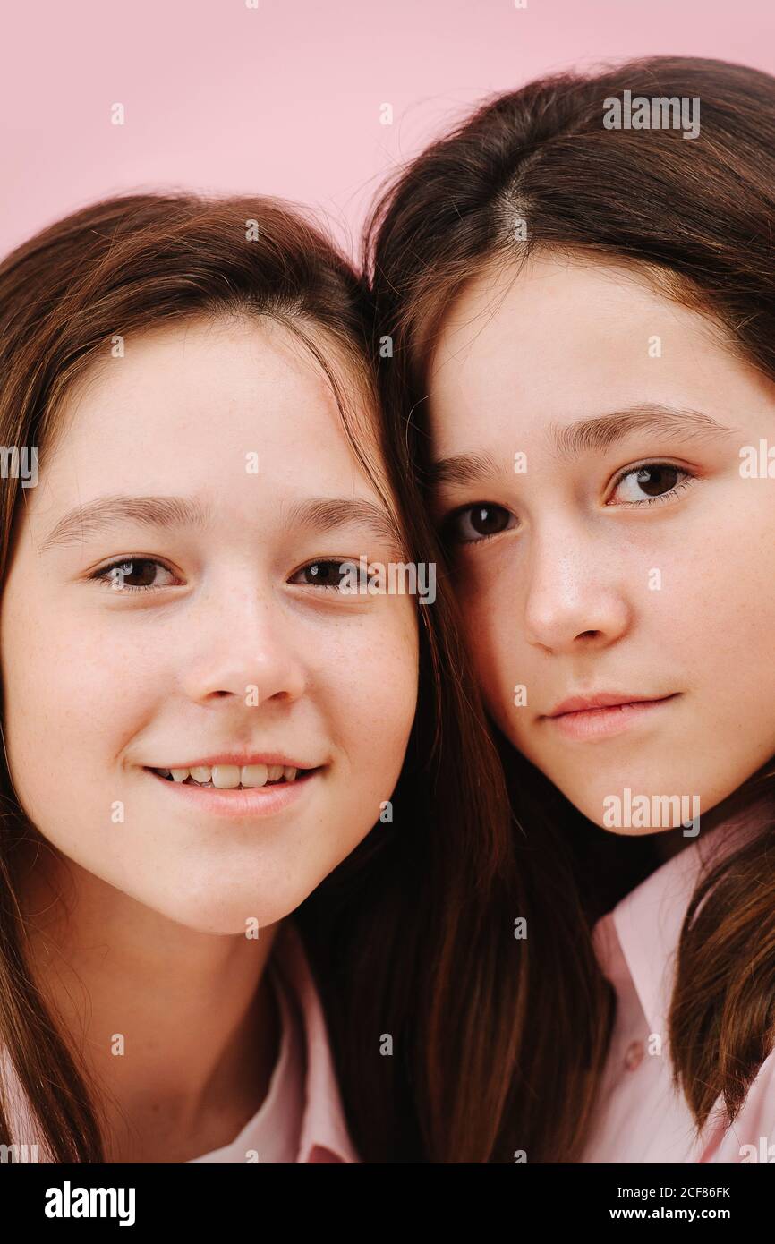 Beautiful little twin sisters pressing heads, happily looking at the ...