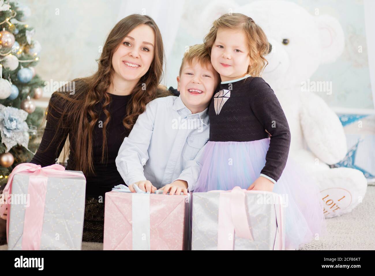 Mother and her two little children with Christmas gift boxes. Family on ...