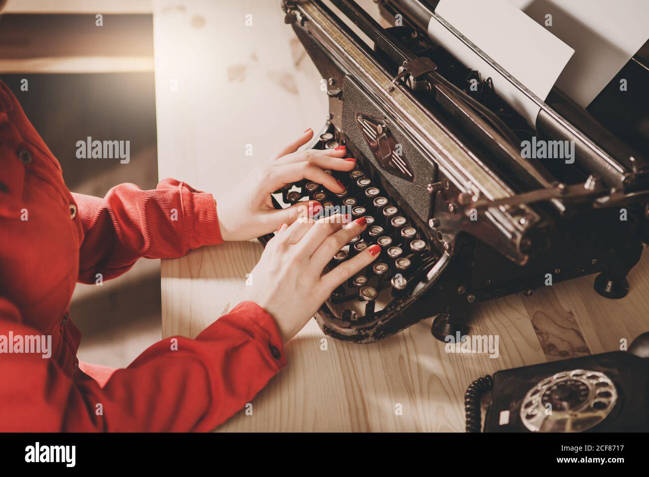 Secretary at old typewriter with telephone. Young woman using ...