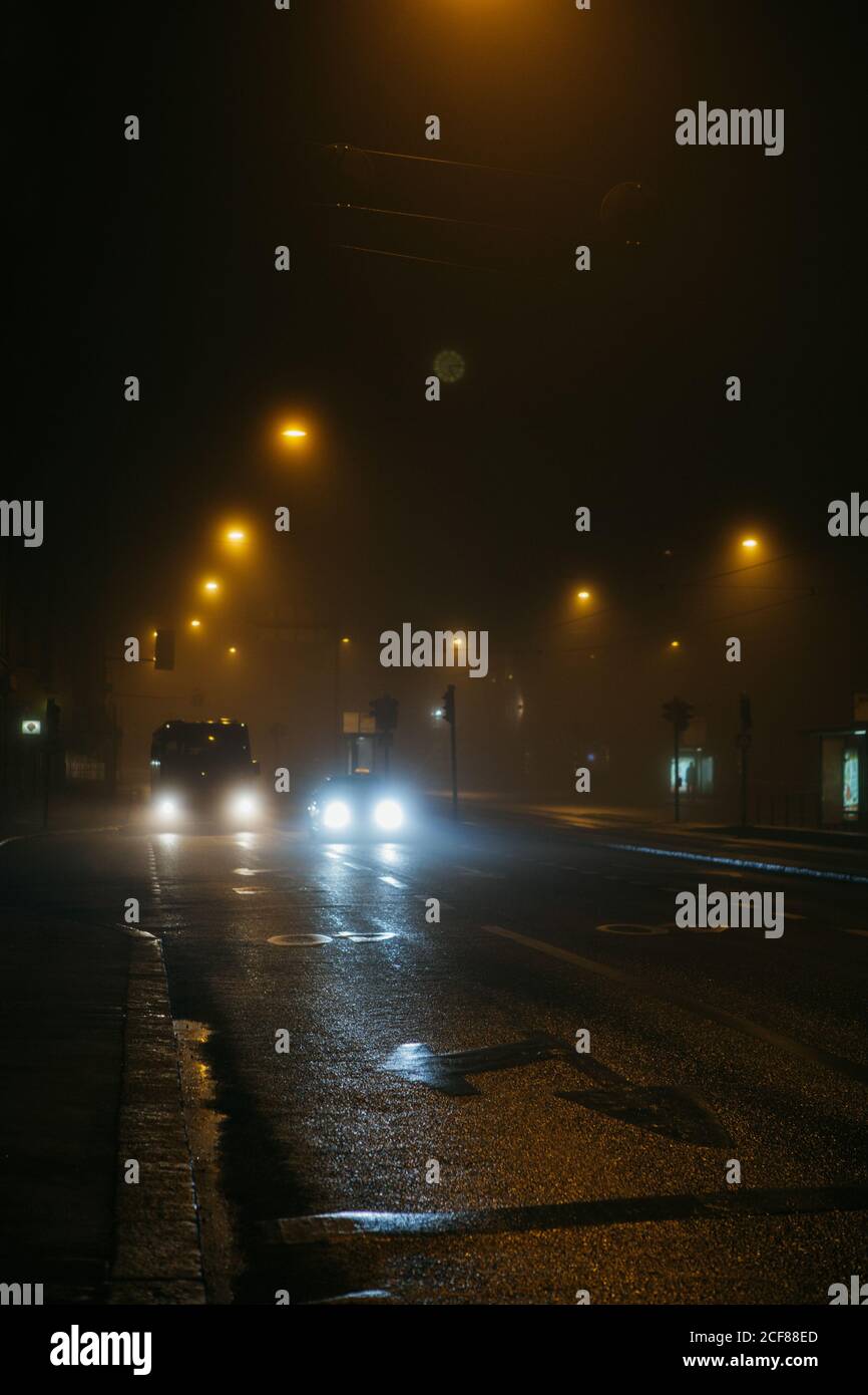 Hazy city street with cars glowing and driving in thick fog in night ...