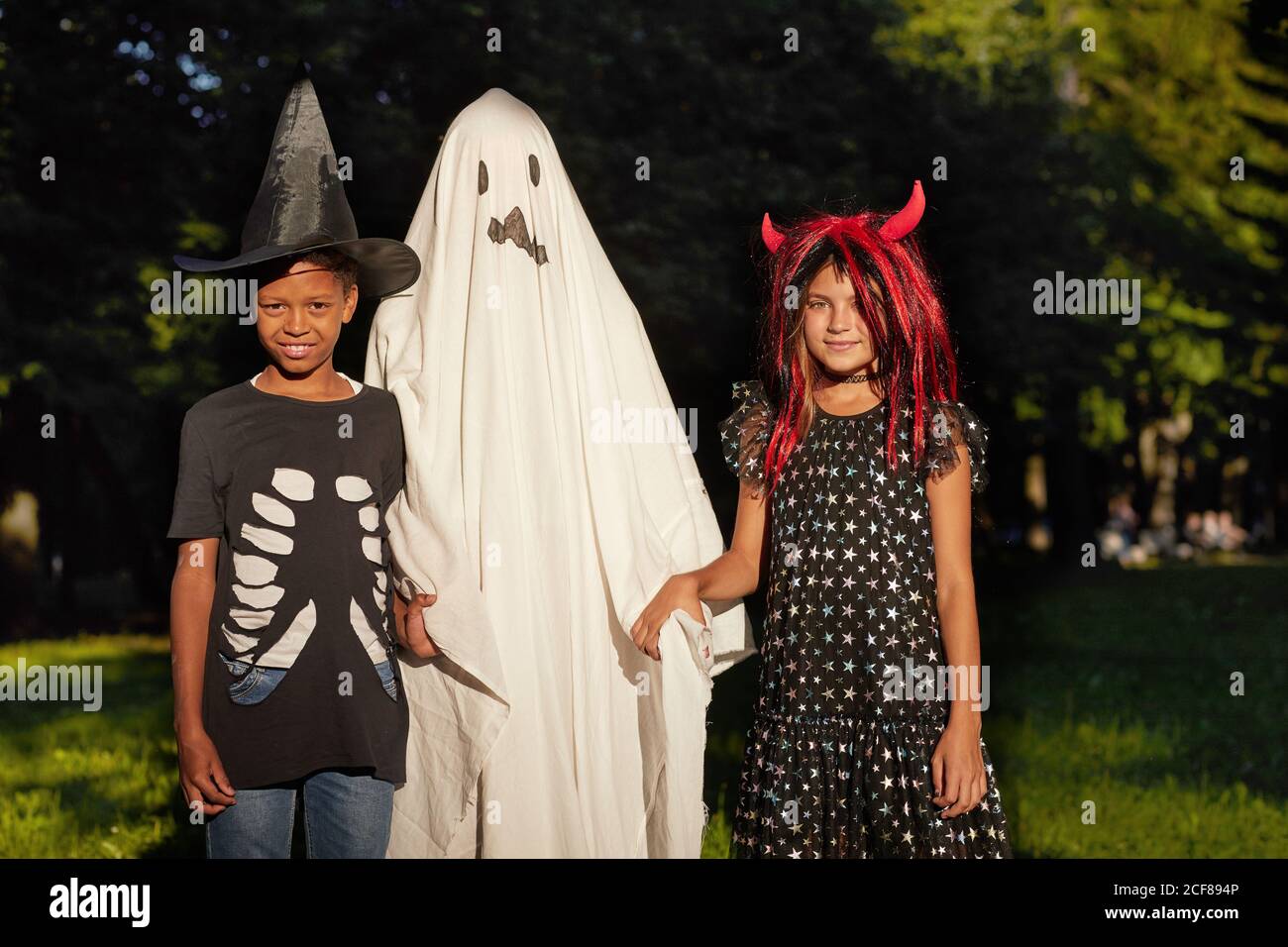 Portrait of children in costumes of witch and ghost smiling at camera ...