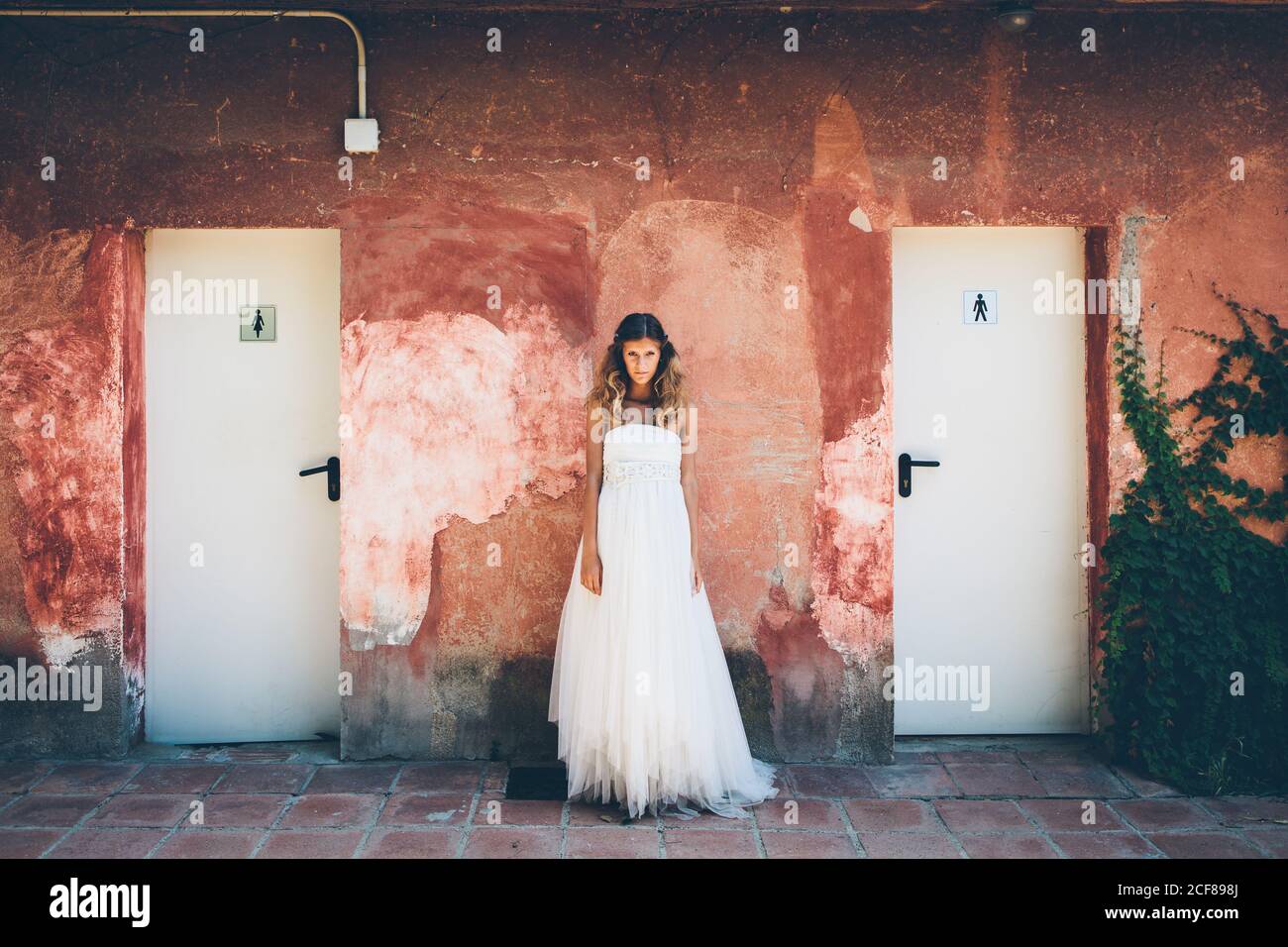 Charming young bride in elegant white wedding dress standing near red ...