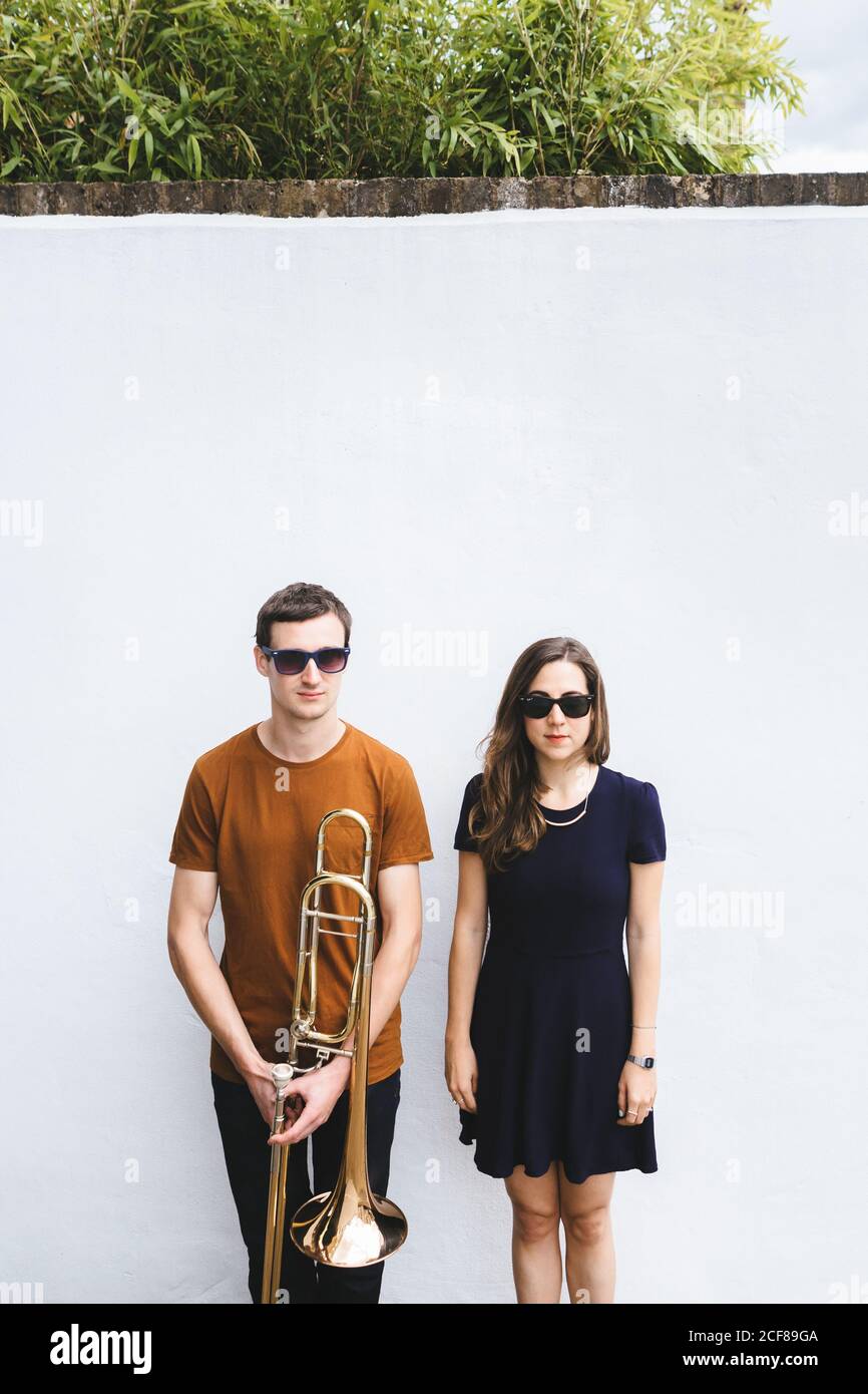 Stylish boyfriend with trombone standing near girlfriend against a ...