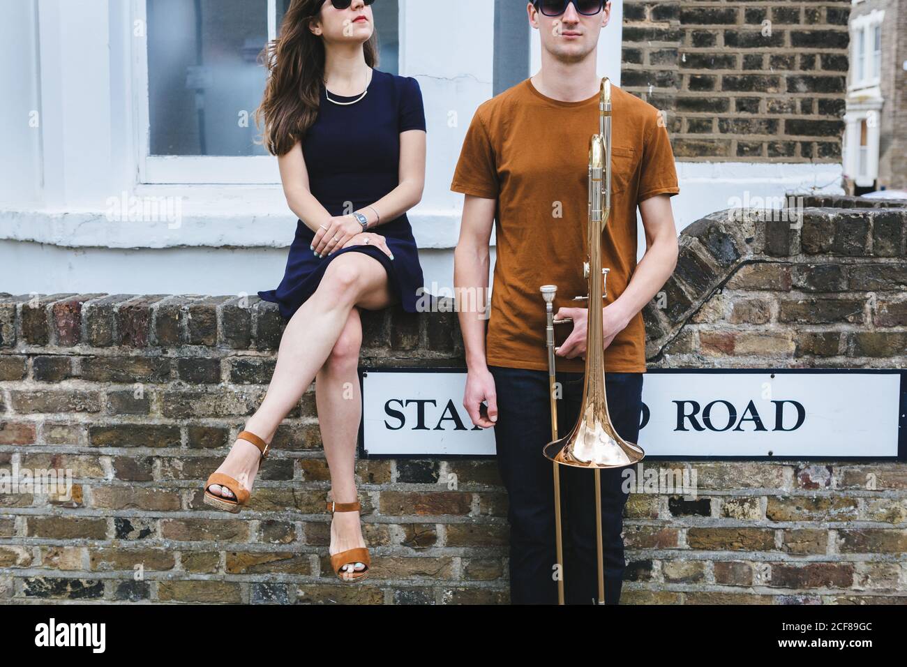 Crop view of stylish boyfriend with trombone standing near girlfriend ...