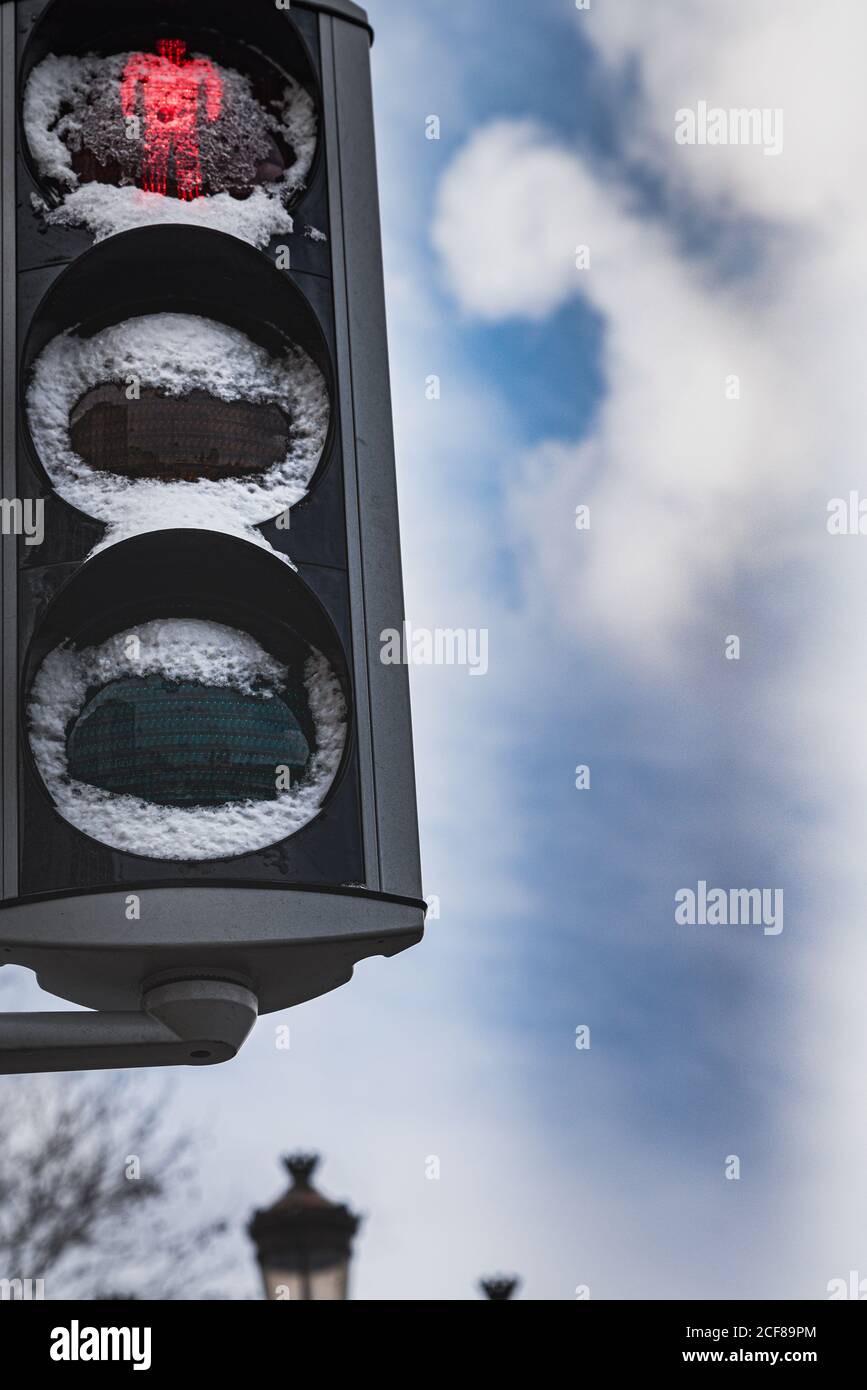 A pedestrian traffic light or semaphore covered with snow is red ...
