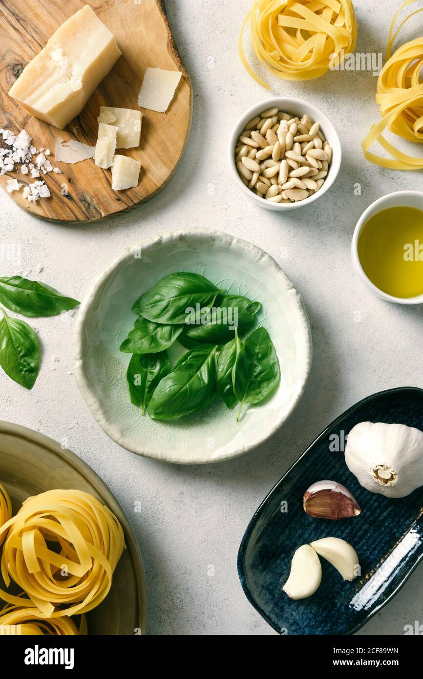 Basil leaves and ingredients for pesto sauce on plates on table Stock ...