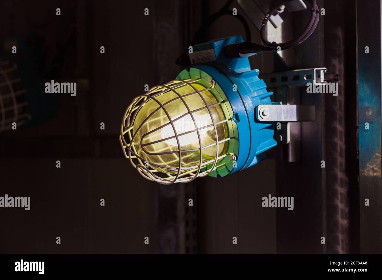 Old industrial lightning with luminous bulb protected by metal grid ...