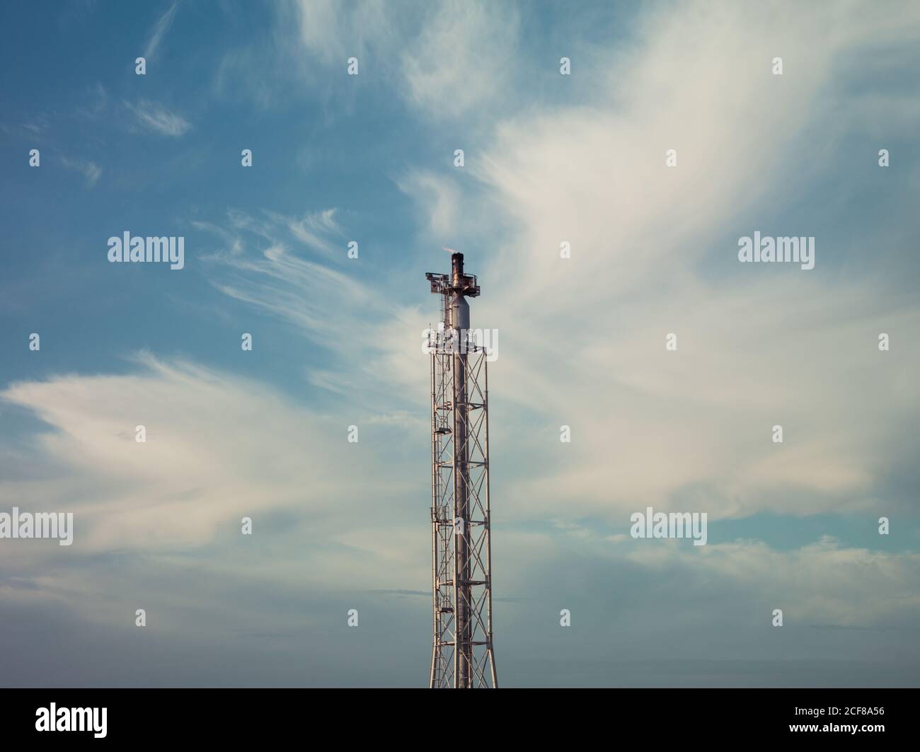 From below of flame releasing from tube of flare stack at petroleum ...