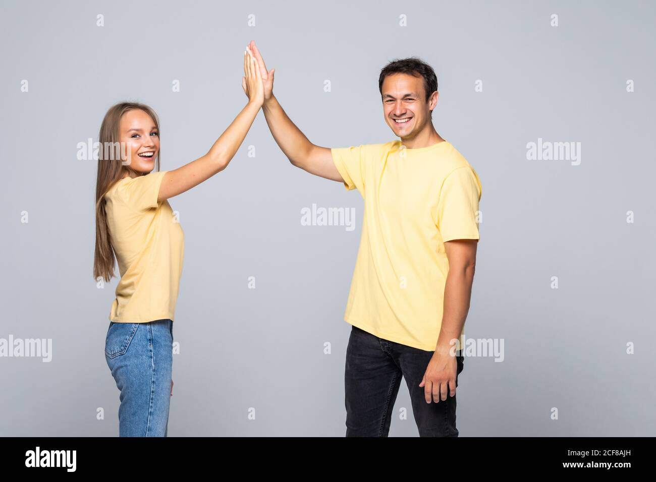 Portrait of a beautiful young couple standing and giving high five ...