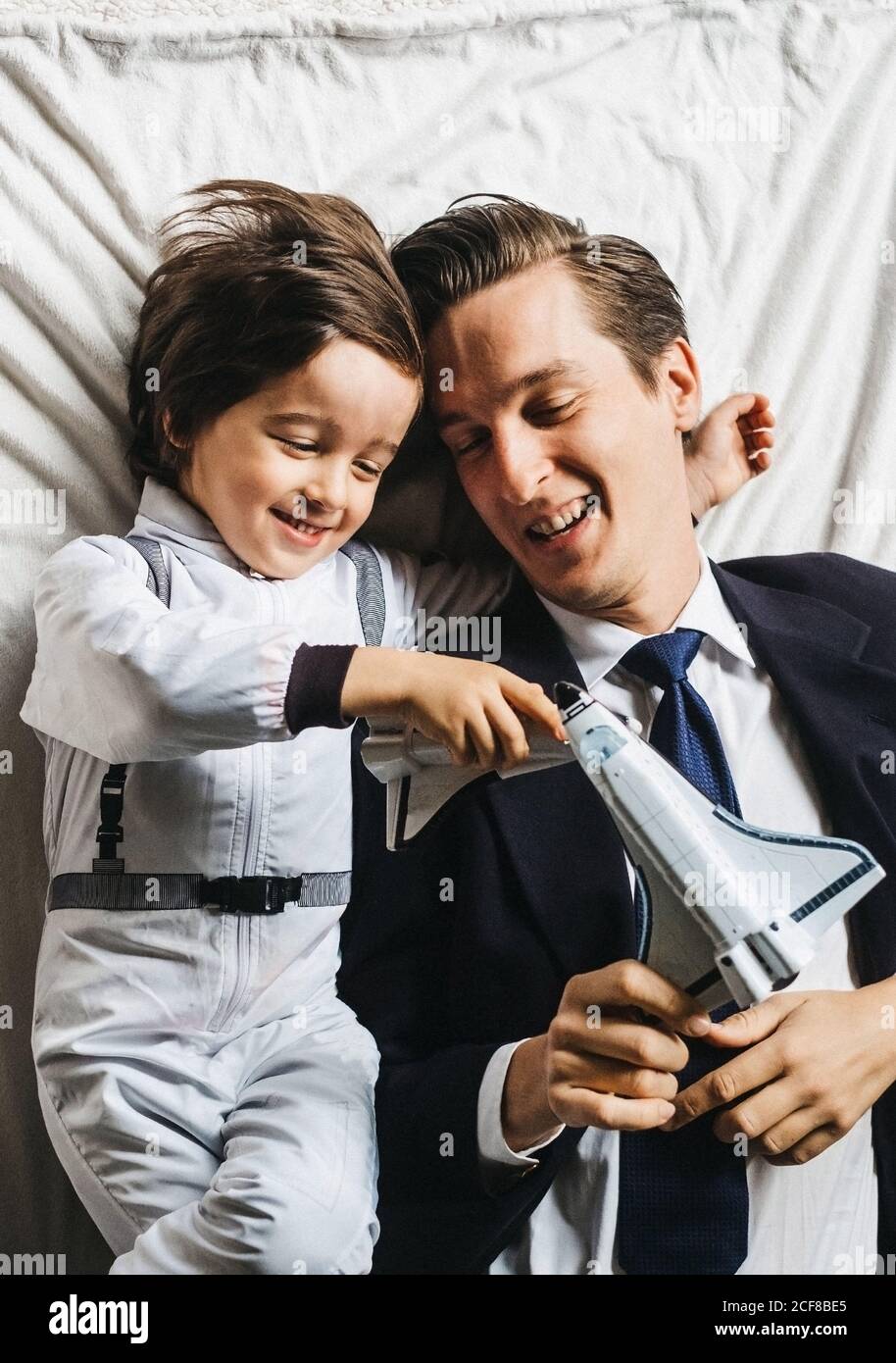 From above of cheerful boy in astronaut costume and dad in formal suit ...