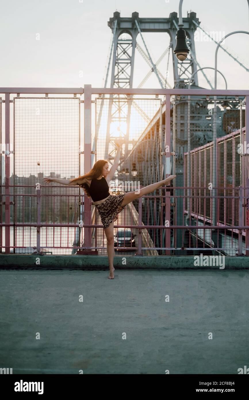 Side view of graceful female dancer in skirt balancing on tiptoe with ...