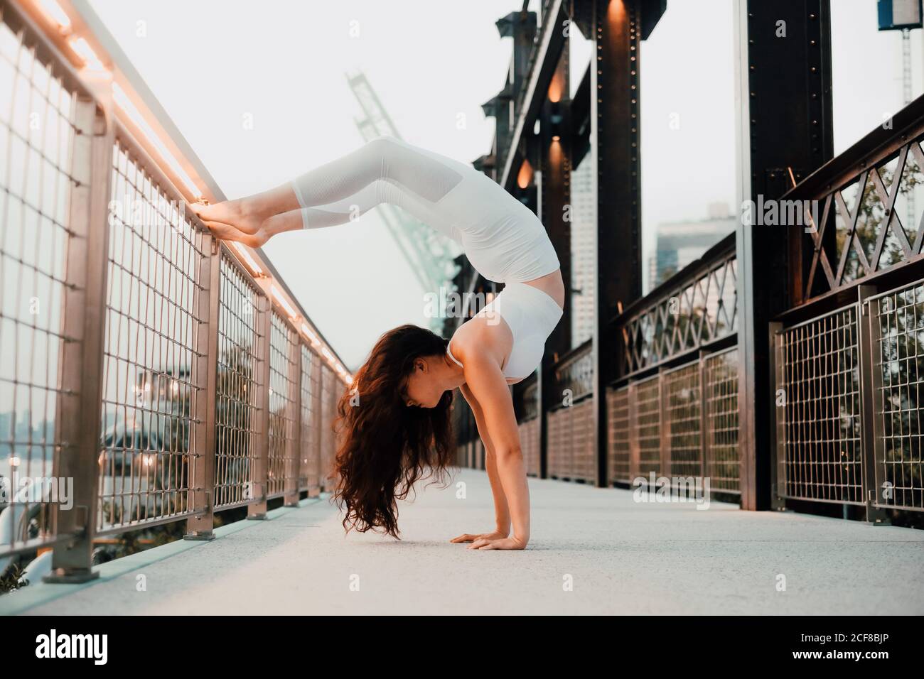 Low angle side view of flexible female in sports bra and leggings ...