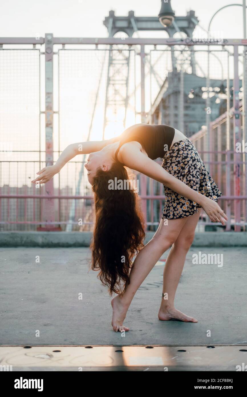 Side view of young graceful female dancer in casual skirt performing ...