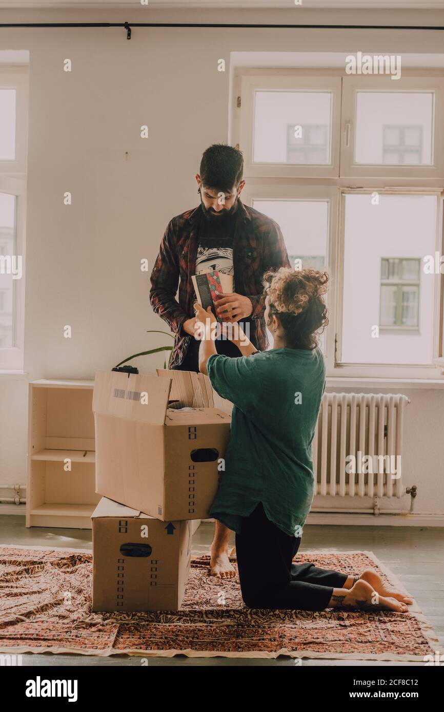 Hipster couple unpacking together boxes while standing barefoot in ...