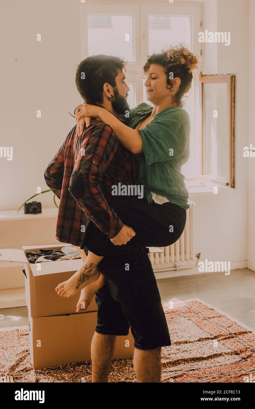 Side View Of Affectionate Couple Cuddling And Front Carrying While