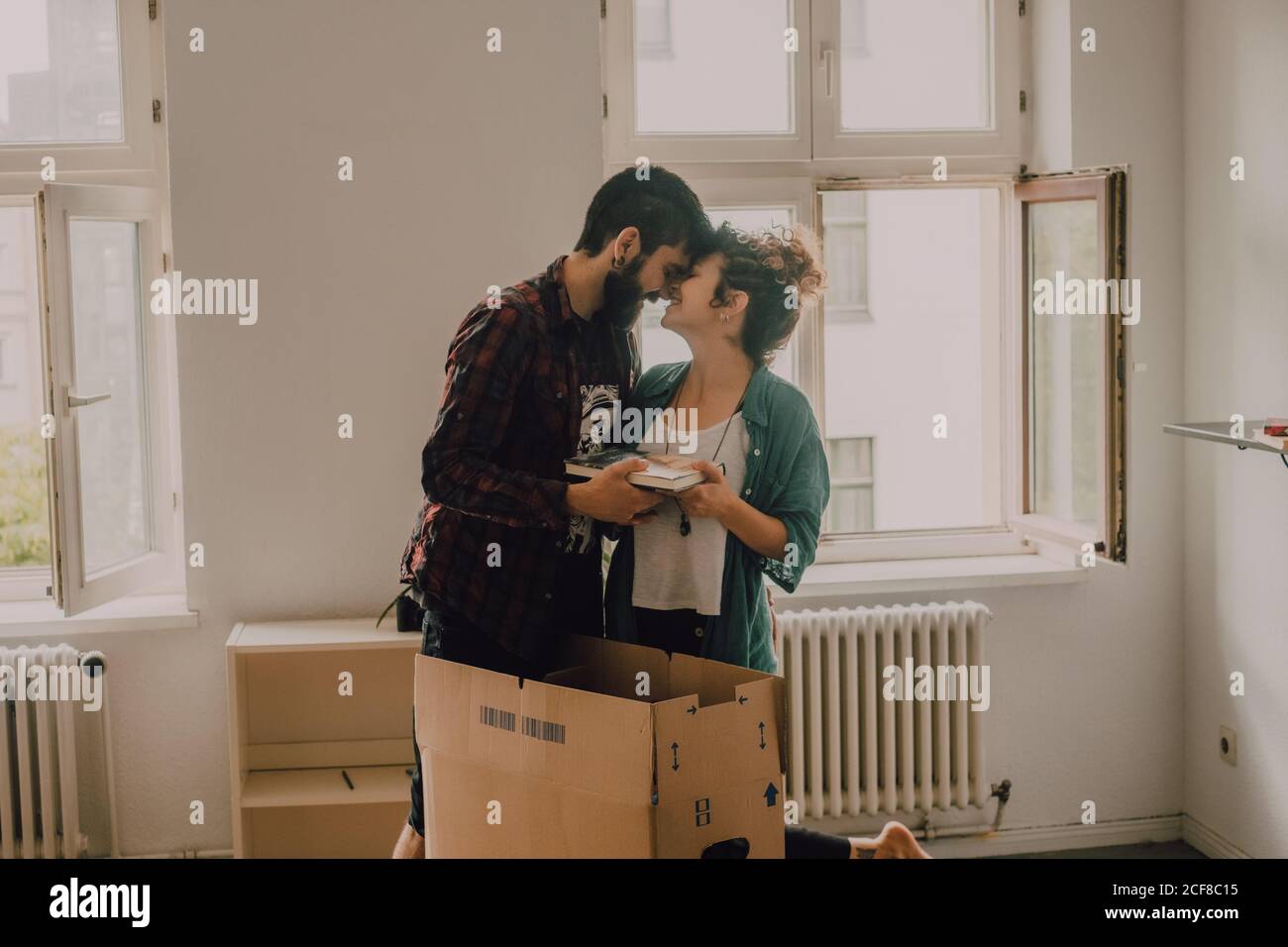 Hipster couple unpacking together boxes while standing barefoot in ...