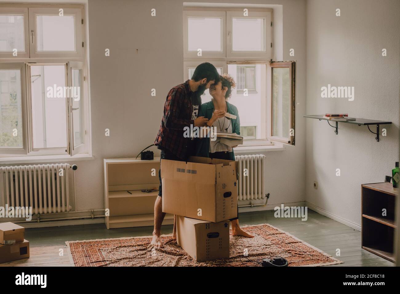Hipster couple unpacking together boxes while standing barefoot in ...