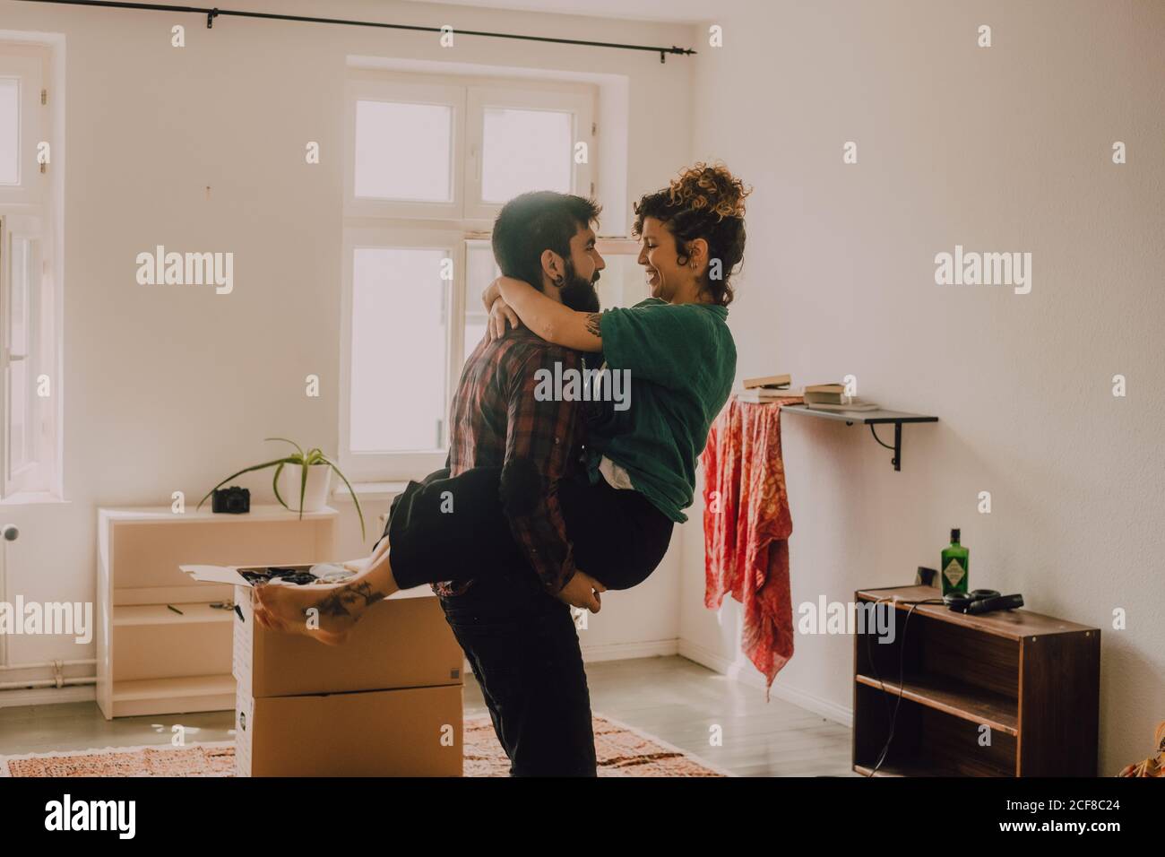 Side view of affectionate couple cuddling and front carrying while ...