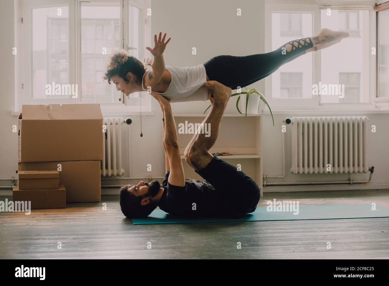 Side view of athletic couple exercising and balancing together on floor ...