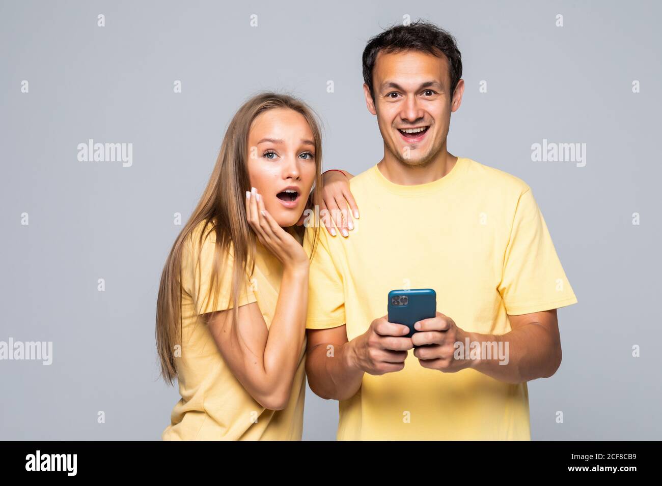 Couple having smart phones in hands, looking at screen, surprised ...