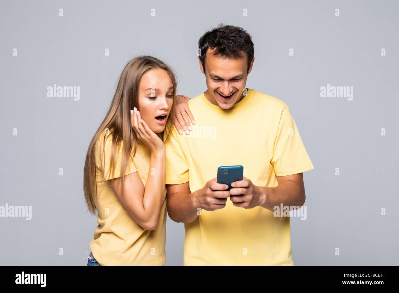 Couple having smart phones in hands, looking at screen, surprised ...