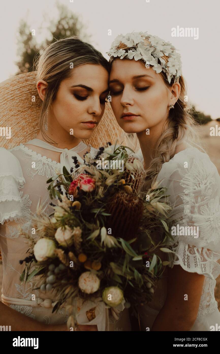 Charming slim brides with flowers in garden with olive trees Stock ...