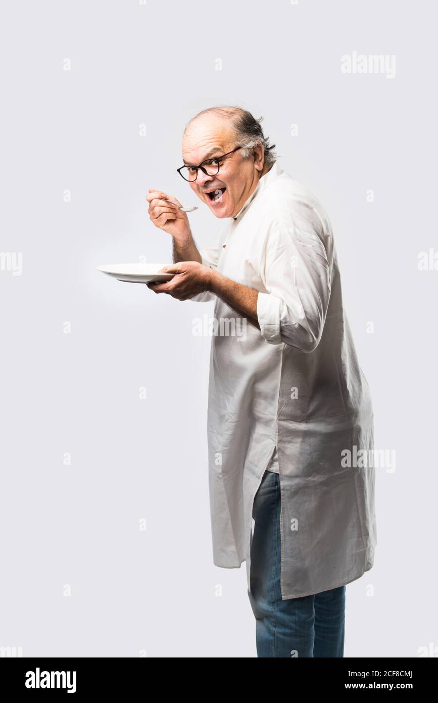 Senior or Old Indian asian man eating from empty white plate or bowl ...