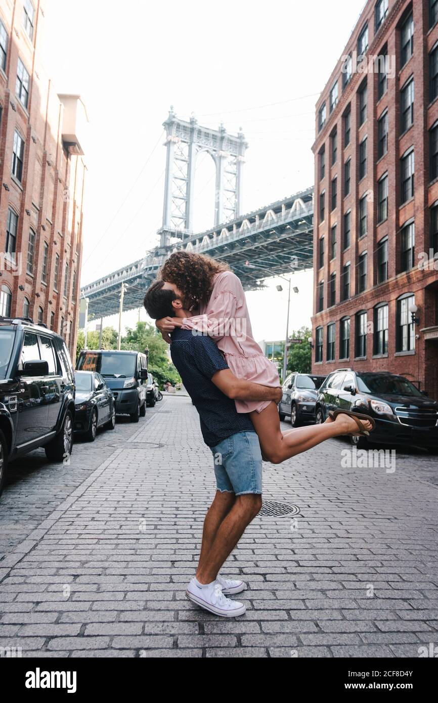 Side view of boyfriend lifting girlfriend while standing on street in ...