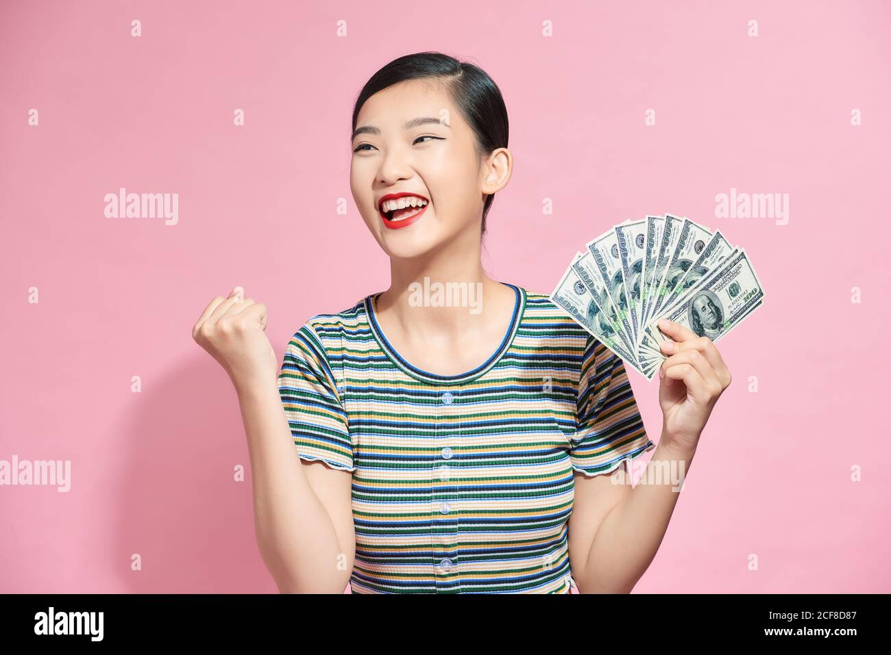 Portrait of a cheerful young woman holding money banknotes and ...