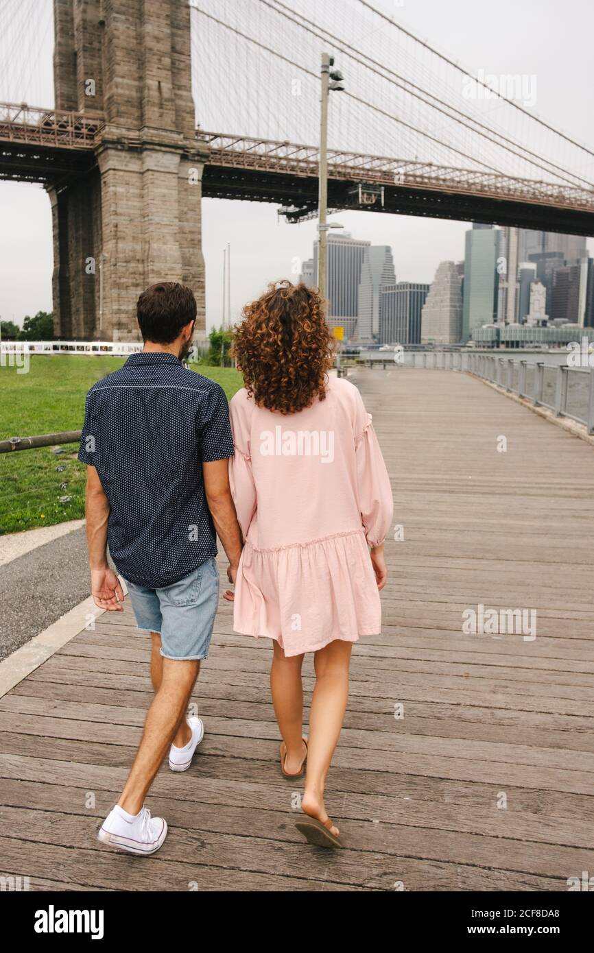 Back view of happy couple in casual wear on wooden promenade during ...