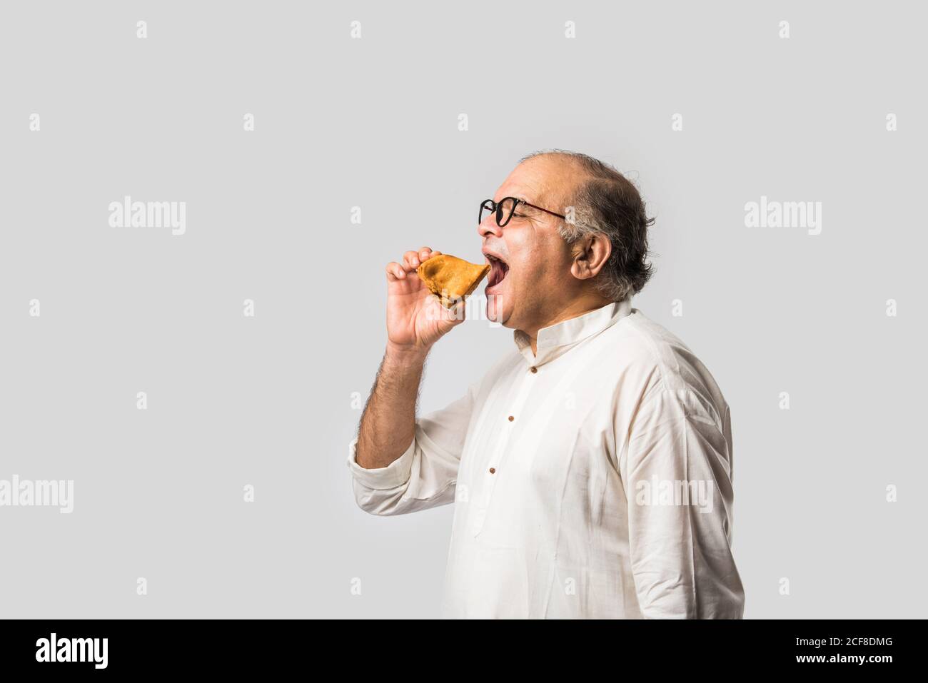 Indian old man or senior man eating samosa or veg pastry Stock Photo ...