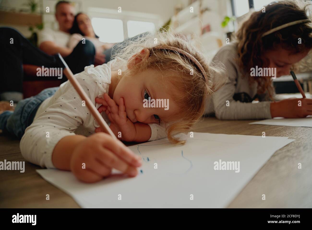 Portrait of two daughter lying on floor drawing artwork on paper at ...