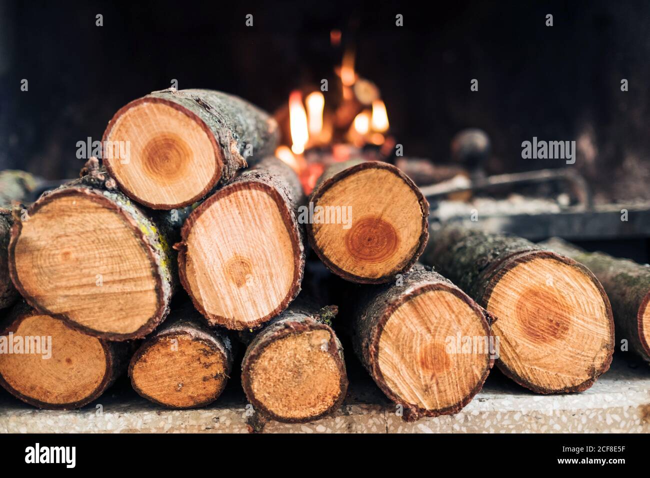 Closeup of fireplace with burning flame and firewood with smoke and ash ...