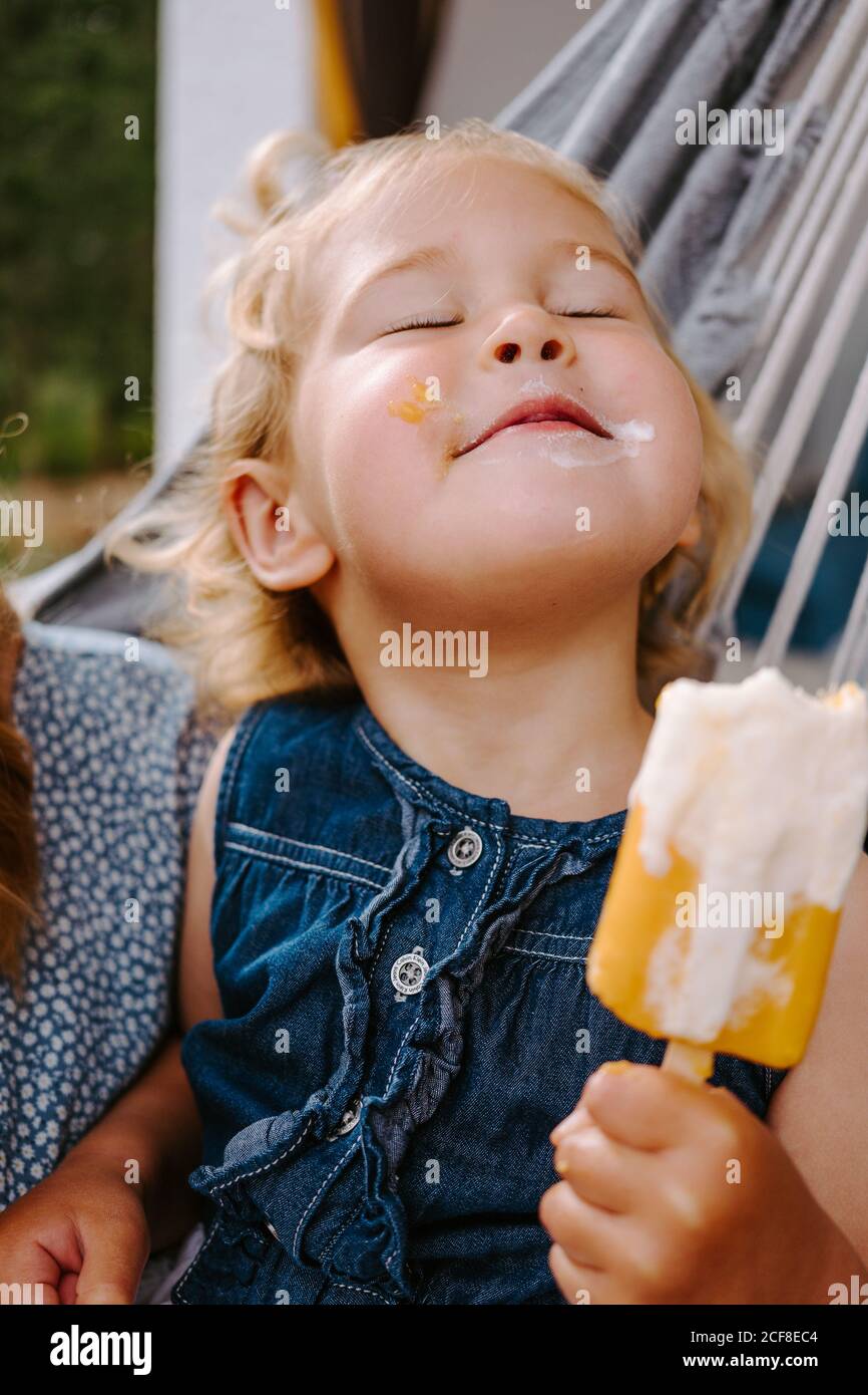 Content little kid eating homemade popsicle on stick while relaxing on ...