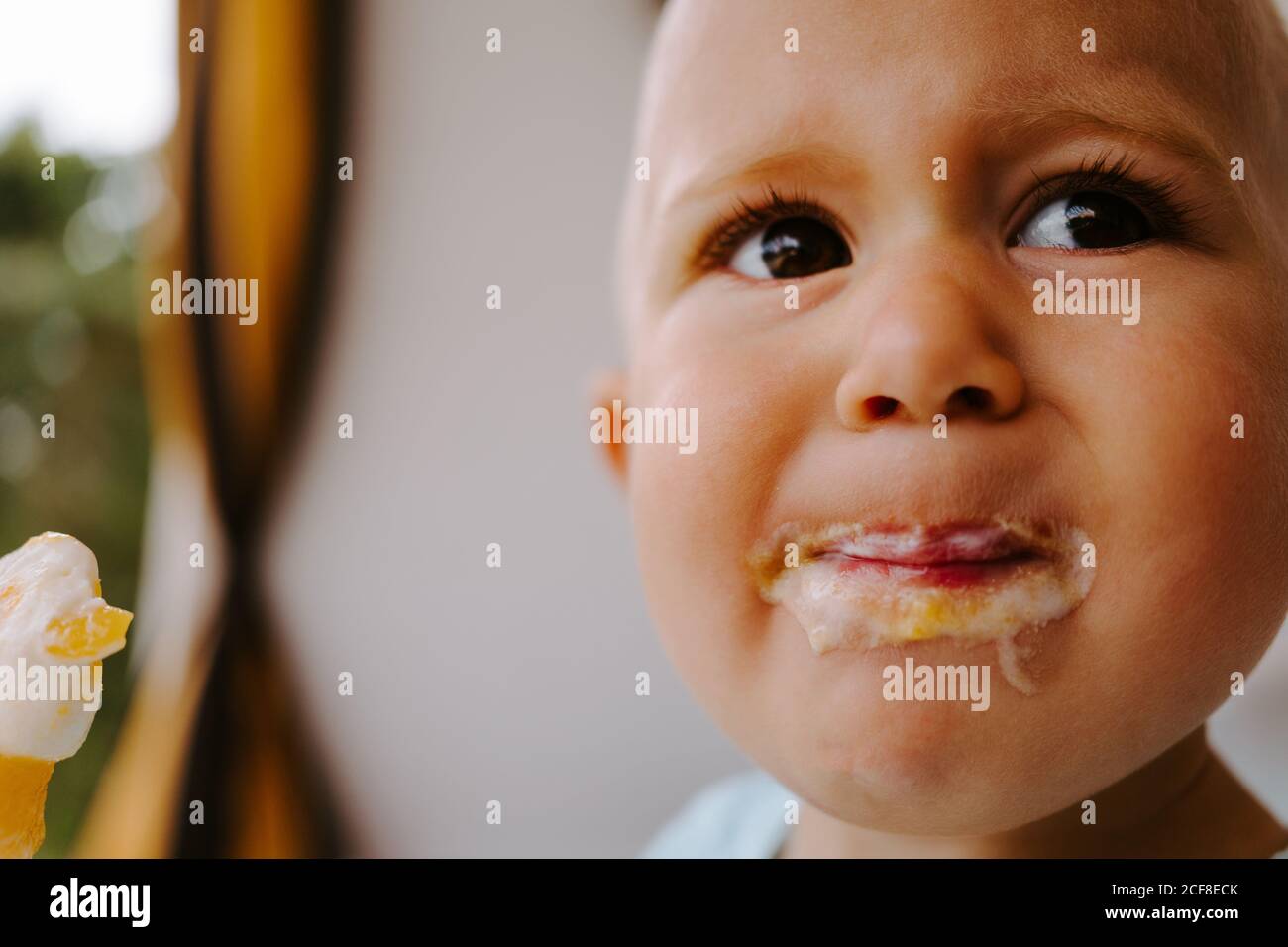 Cute little child looking away with dirty mouth enjoying tasty homemade ...