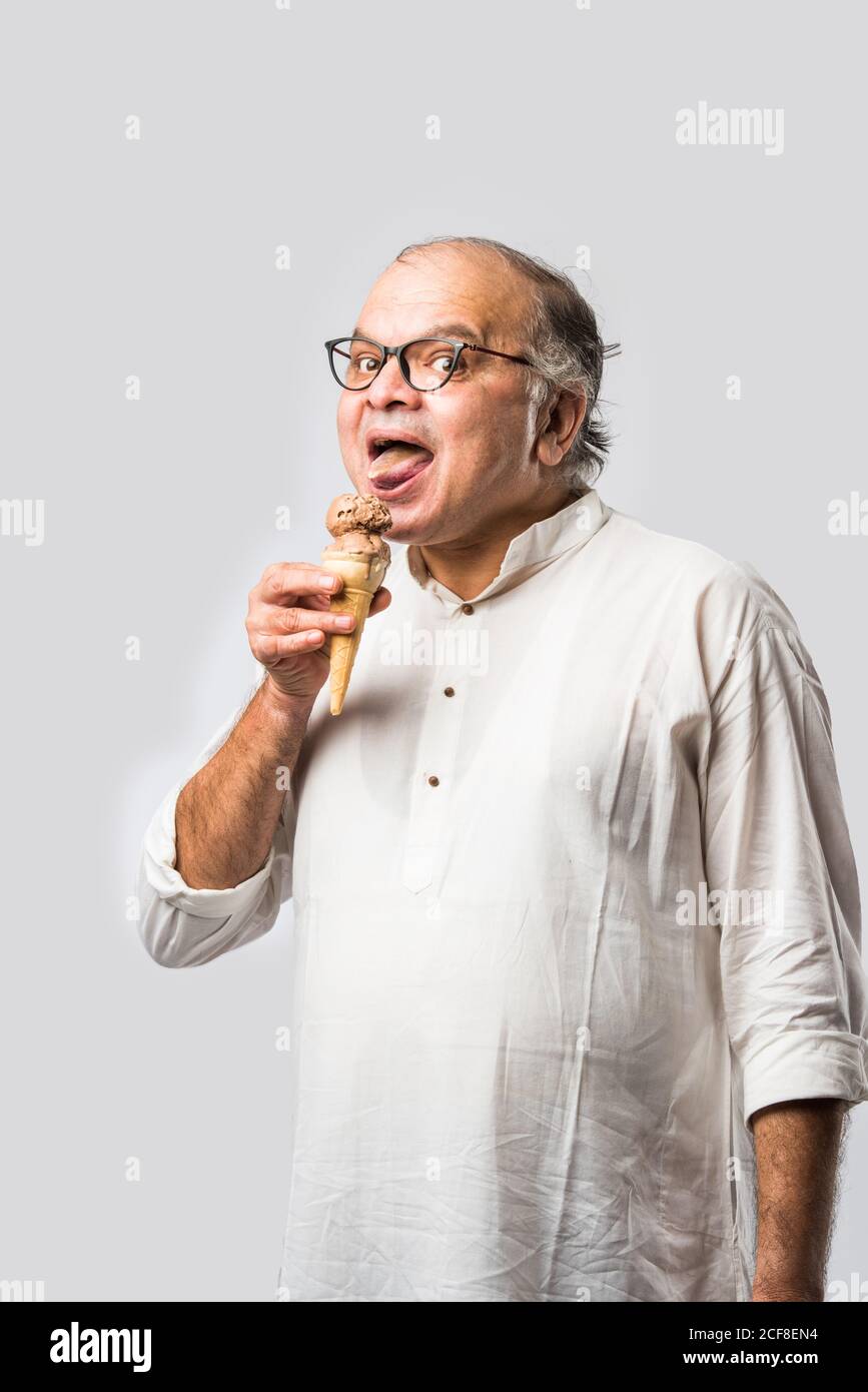 Indian Old man eating chocolate Ice cream in cone or mango candy bar ...