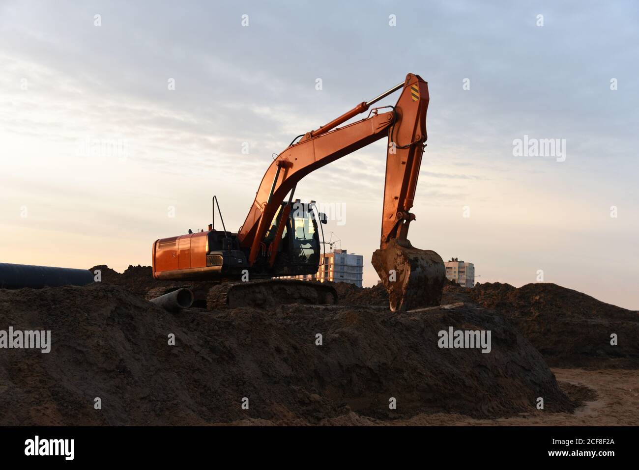 Red excavator during groundwork on construction site. Hydraulic backhoe ...