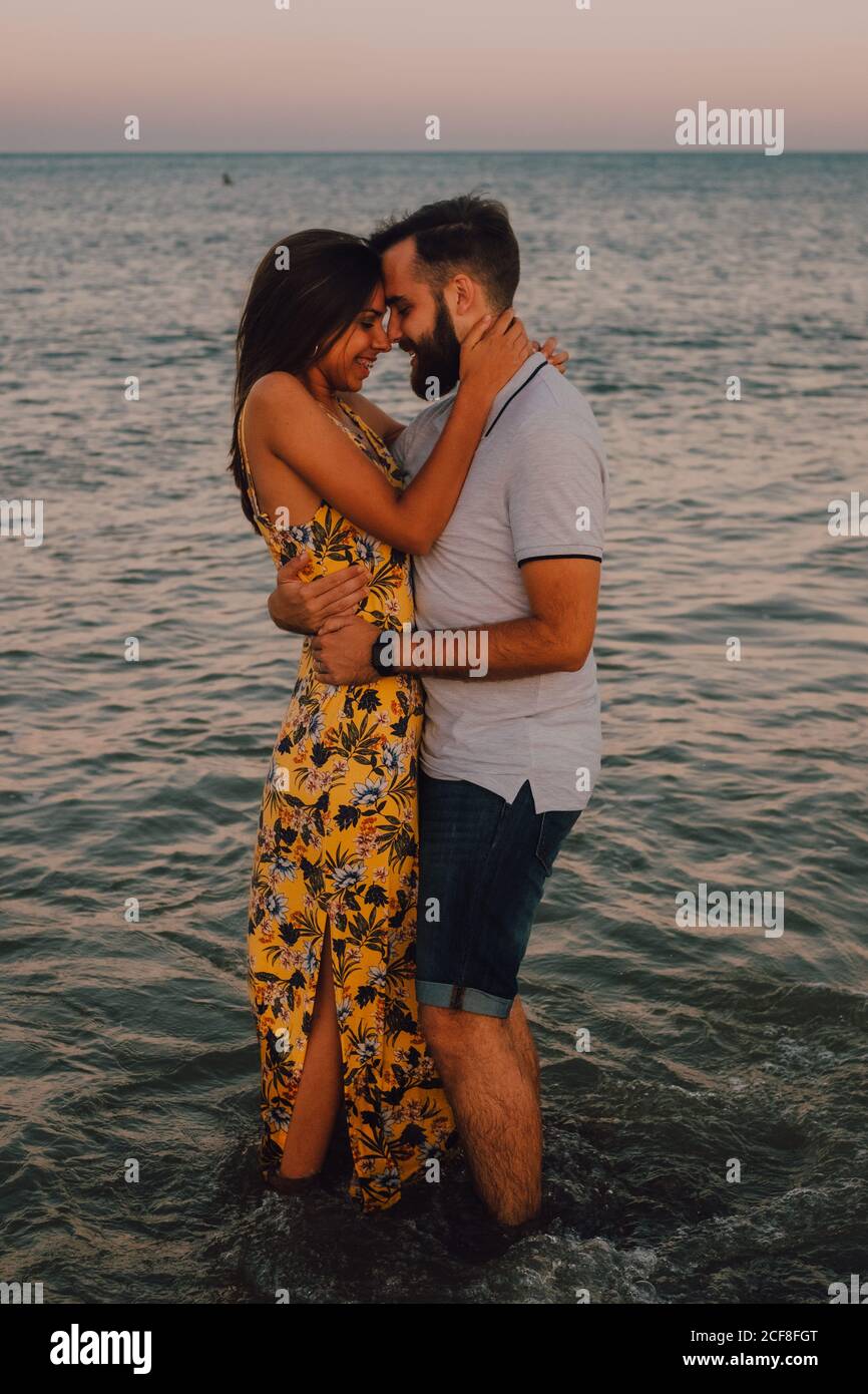 Amorous man hugging Woman while charming lady looking gently at seaside ...