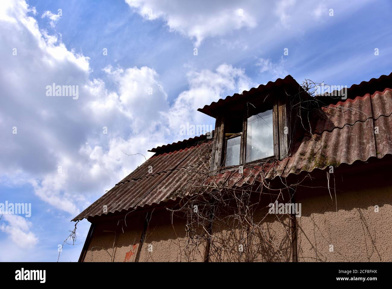 Old destroyed roof window with cracked wooden frame on top of ruins of abandoned suburban family ...