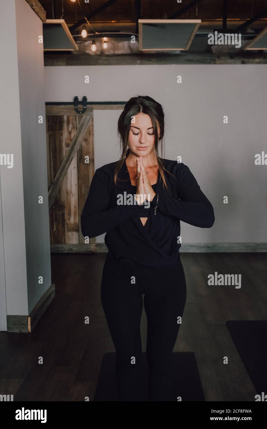 Calm slender Woman in activewear with namaste standing in mountain ...