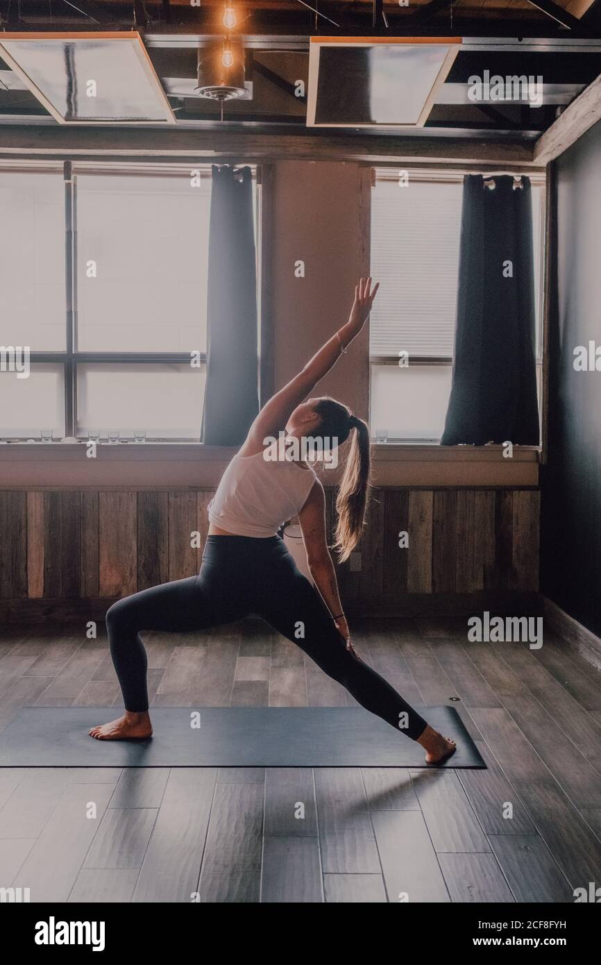 Back view of unrecognizable Woman doing revolved triangle pose exercise ...