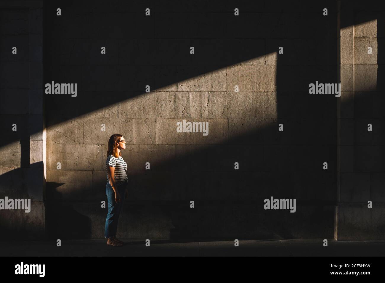 Side view of lady in casual outfit standing in dark passage with ...